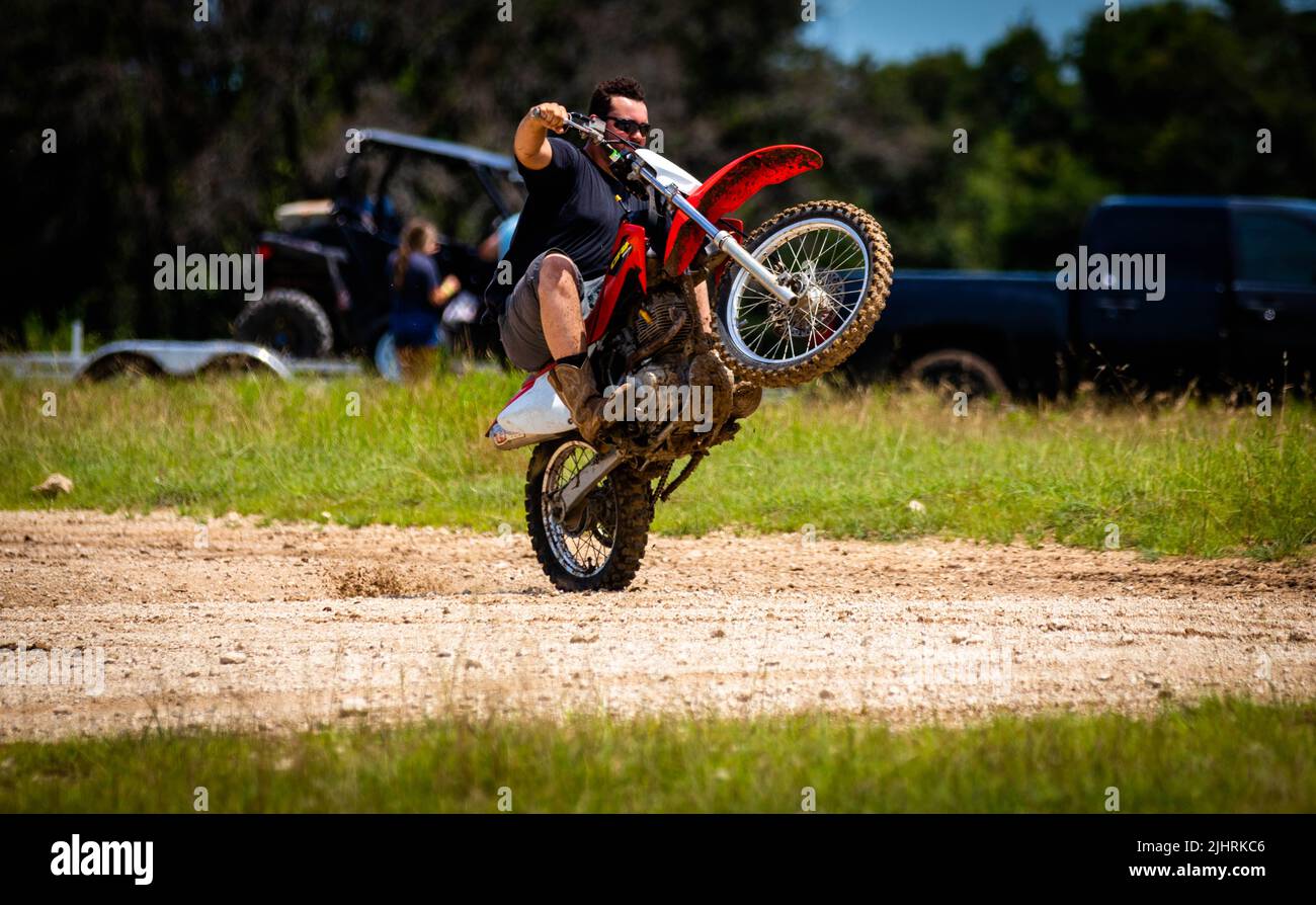 A closeup of a motocross racer stands on a rear wheel of a bike in Fort ...