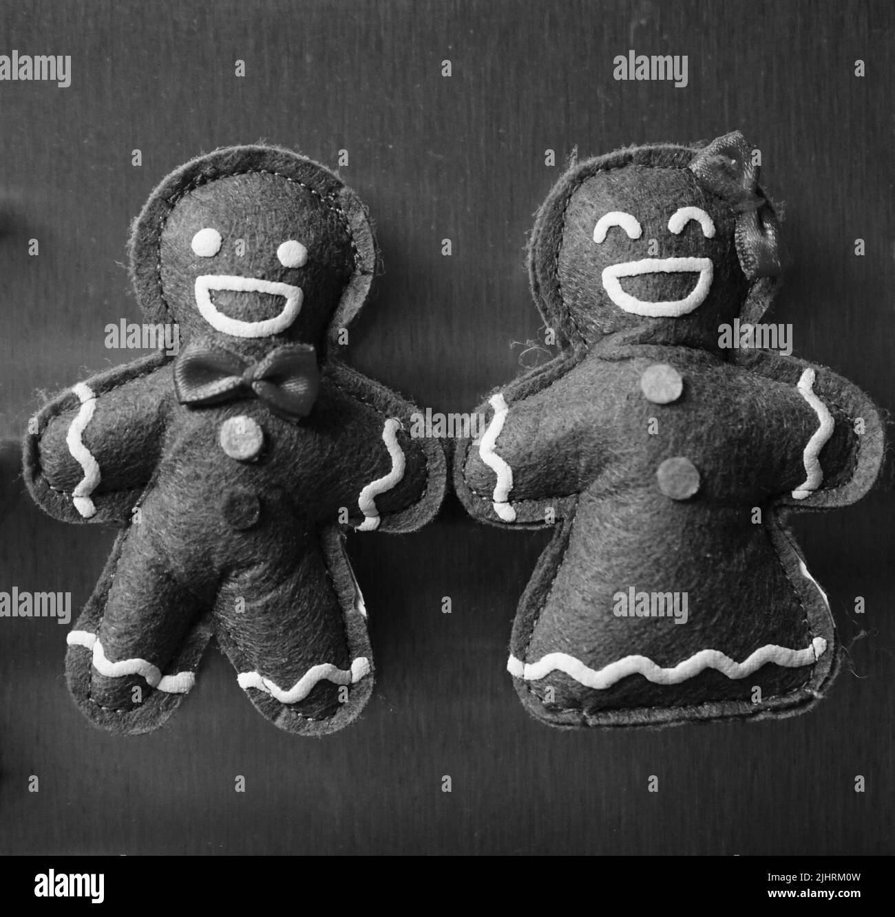 A grayscale closeup of a gingerbread man and a woman magnets on the ...