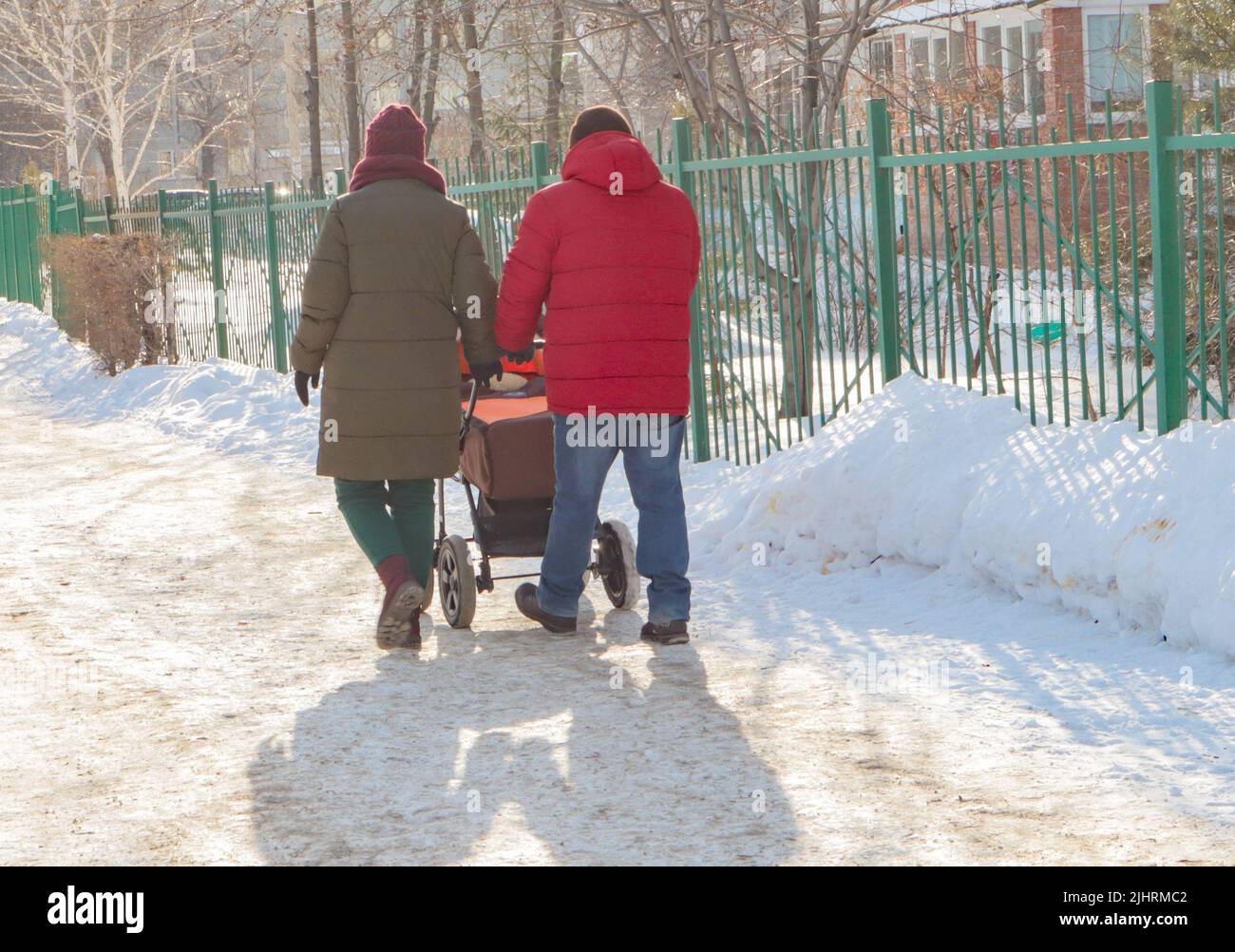 A couple with a baby stroller walks through the winter park during a ...