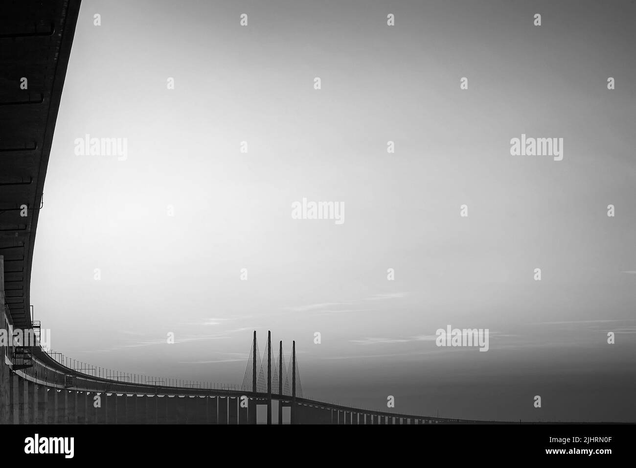 A low angle grayscale of the famous Oresunds bridge in Sweden against a ...