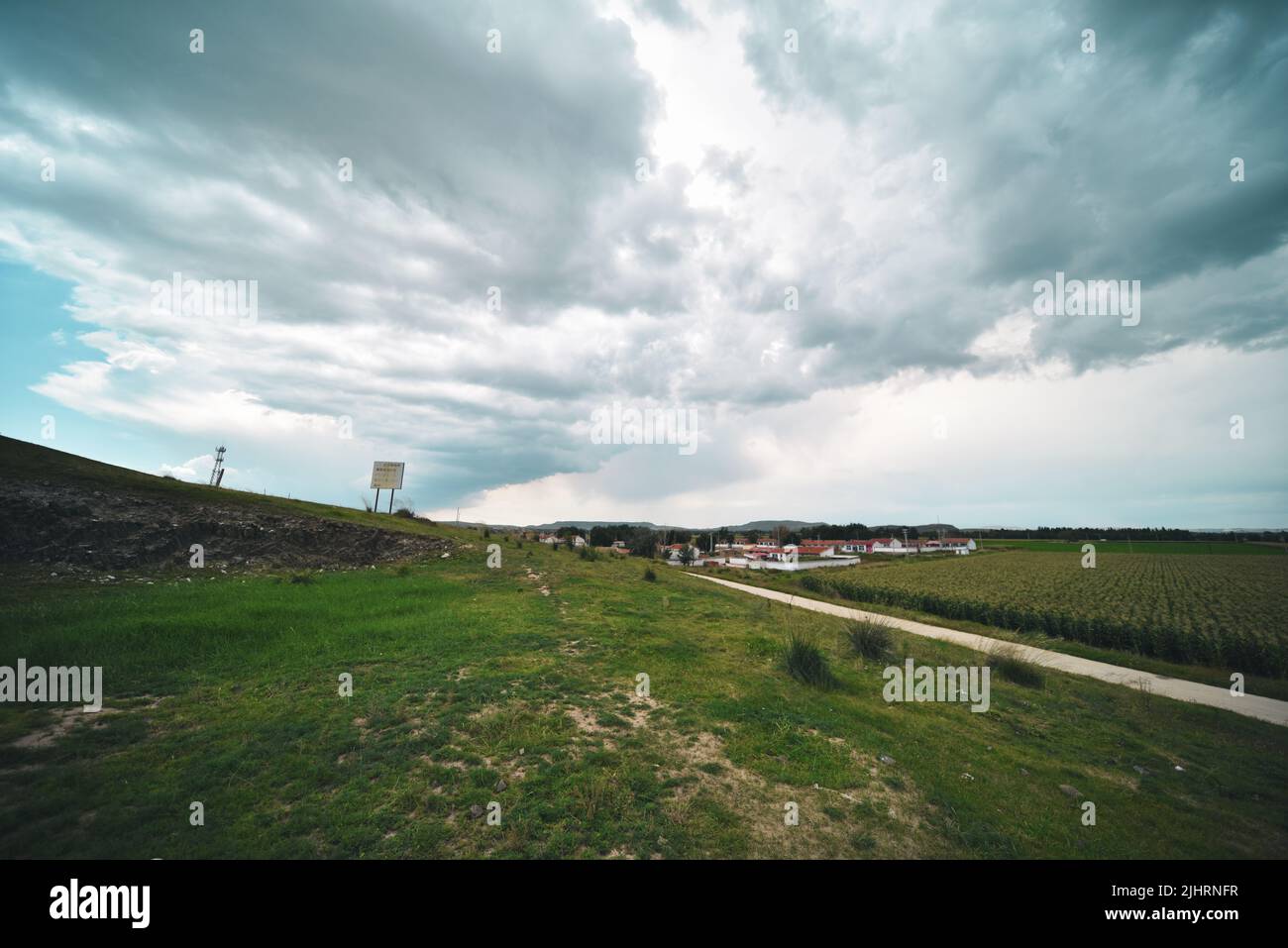 The pathway separating the green fields under the cloudy sky Stock ...
