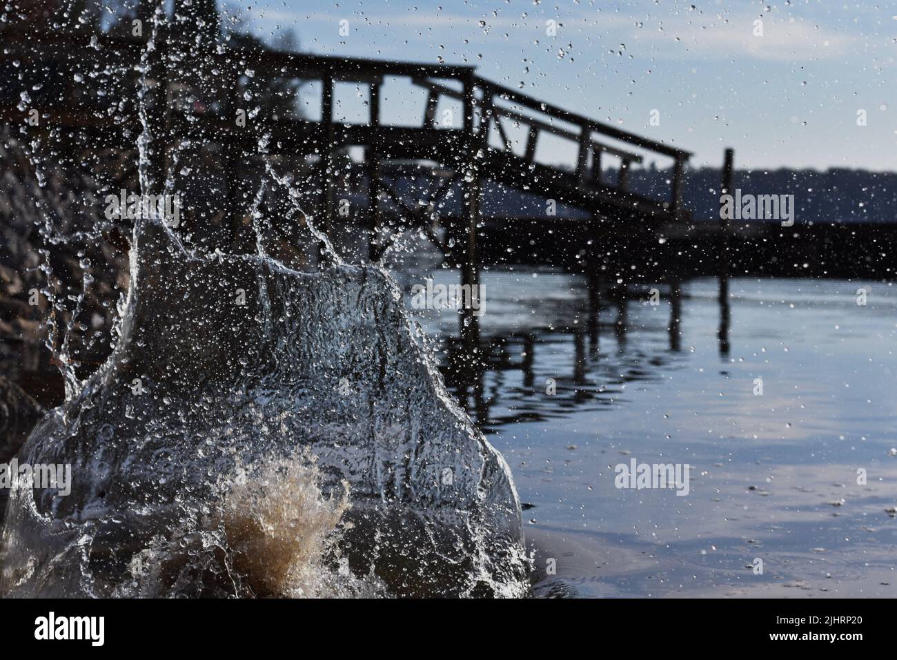 A closeup shot of a stone thrown into the lake making water splash with ...