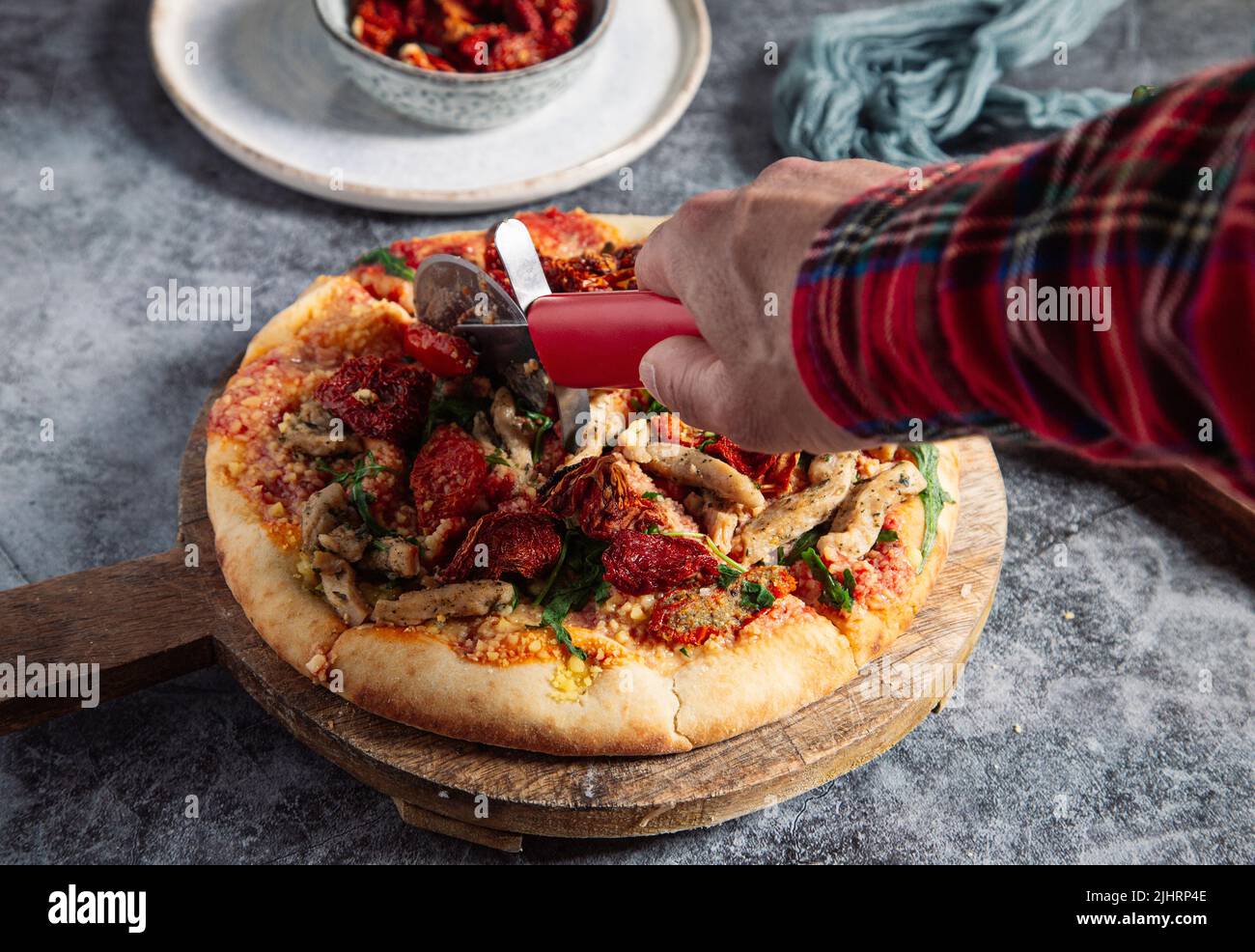 Man's hand holds cutter over hot italian pizza on gray marble ...