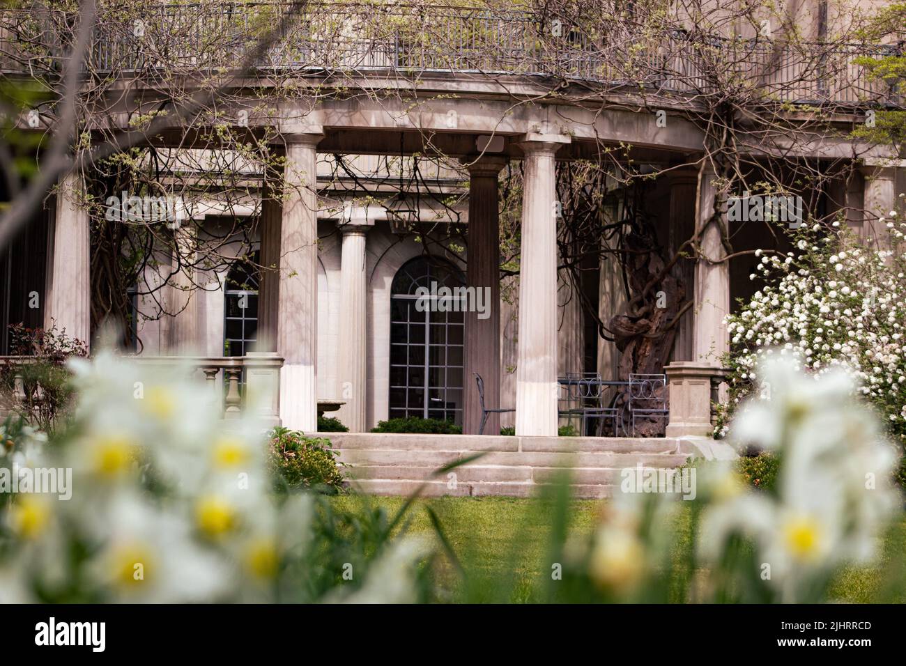A Victorian building with large pillars surrounded by plants Stock ...