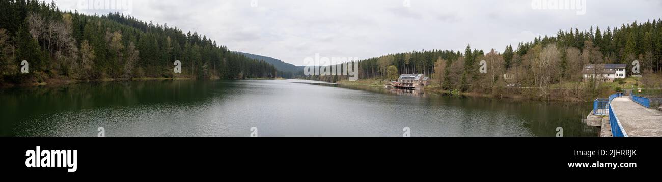A panoramic view of the wide river surrounded by trees, and two houses ...
