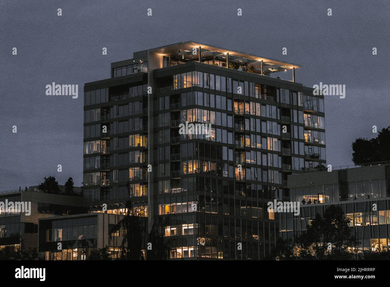 An exterior view of a modern architectural complex at night in cloudy ...