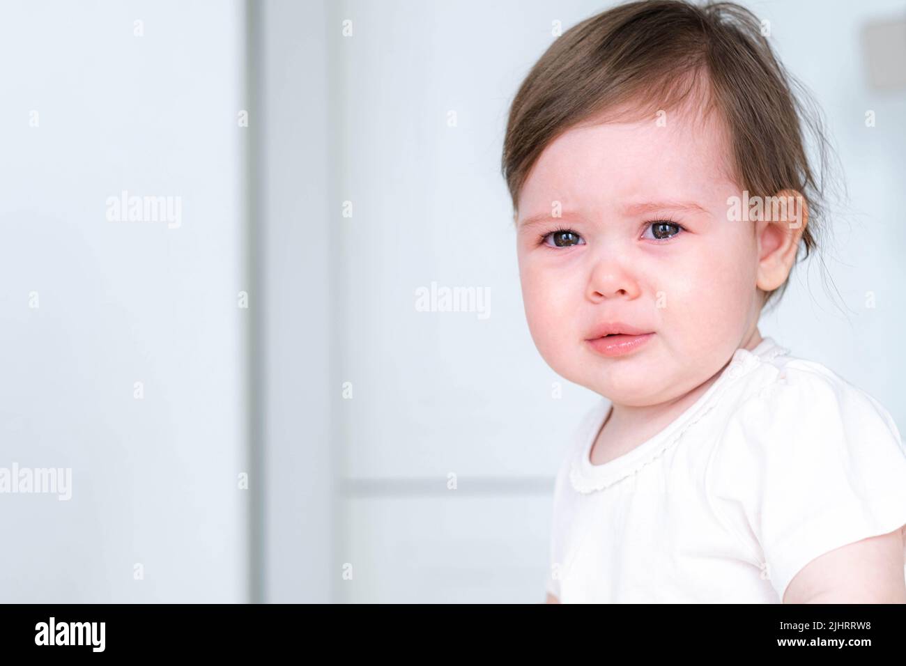 portrait unhappy crying baby child sitting on highchair on kitchen at ...
