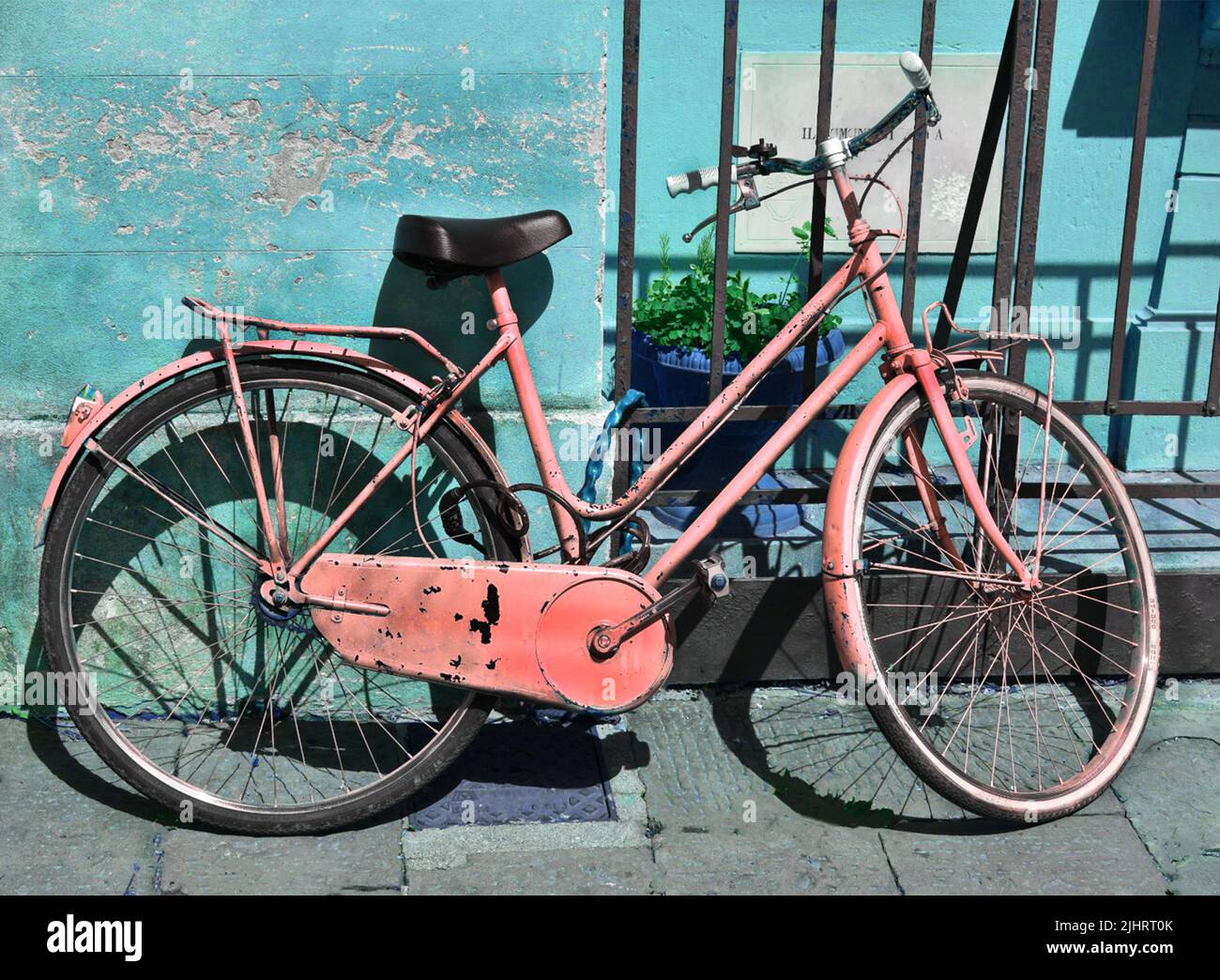 A rusty red bicycle leaning on blue weathered building wall and metal ...