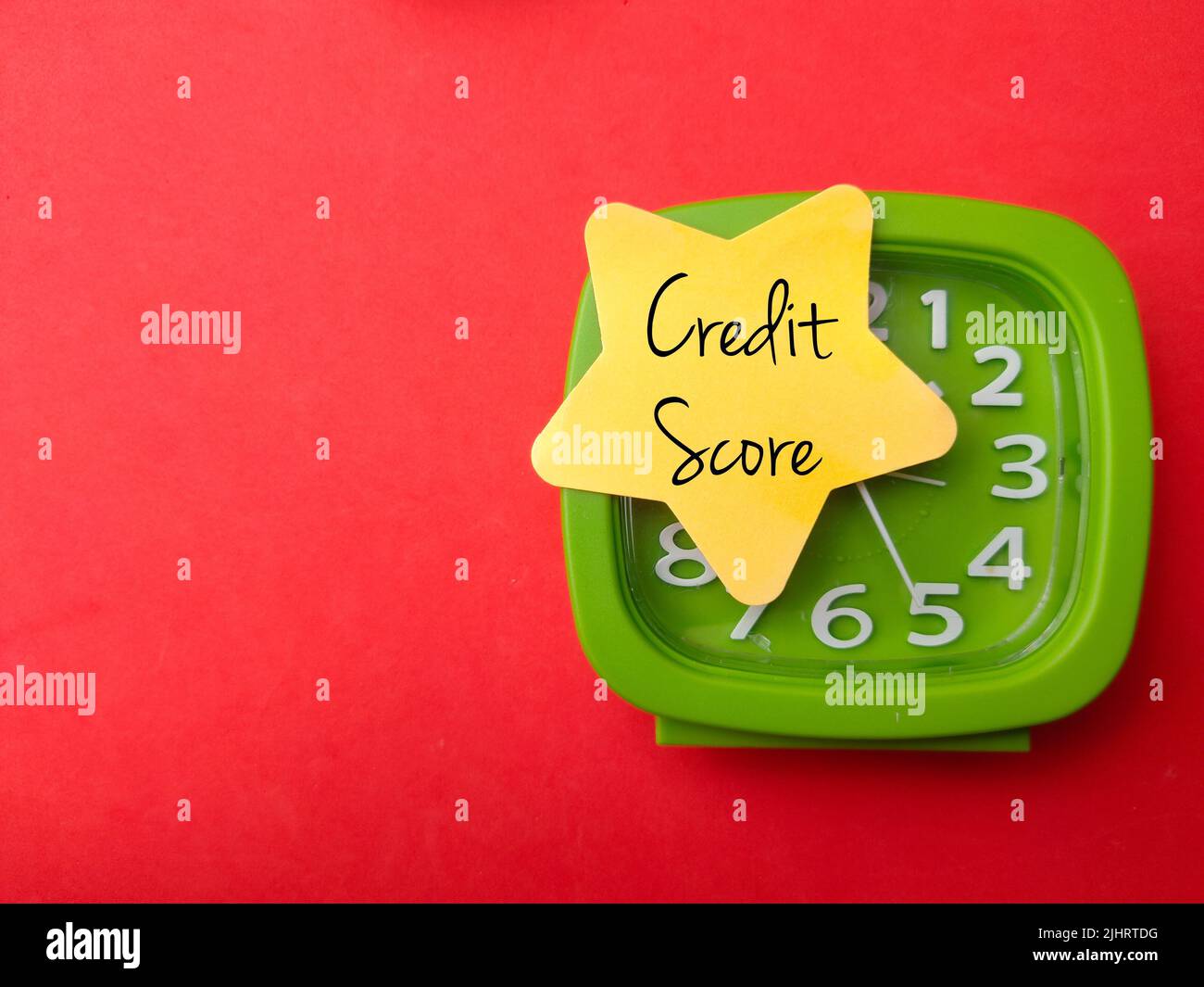 An alarm clock with a colored sticky note with text Credit Score on a ...