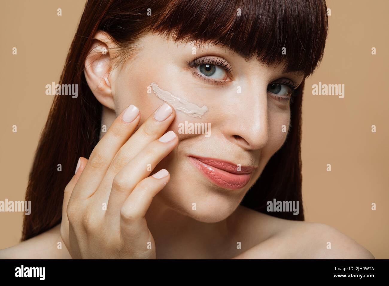 Beauty cosmetics. Close up beautiful red hair woman applying tonal ...