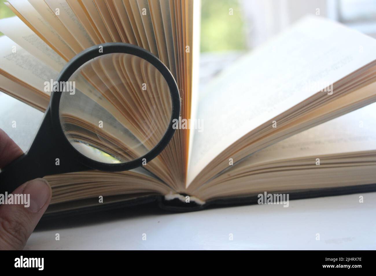 open book with magnifying glass over nature background. Searching ...