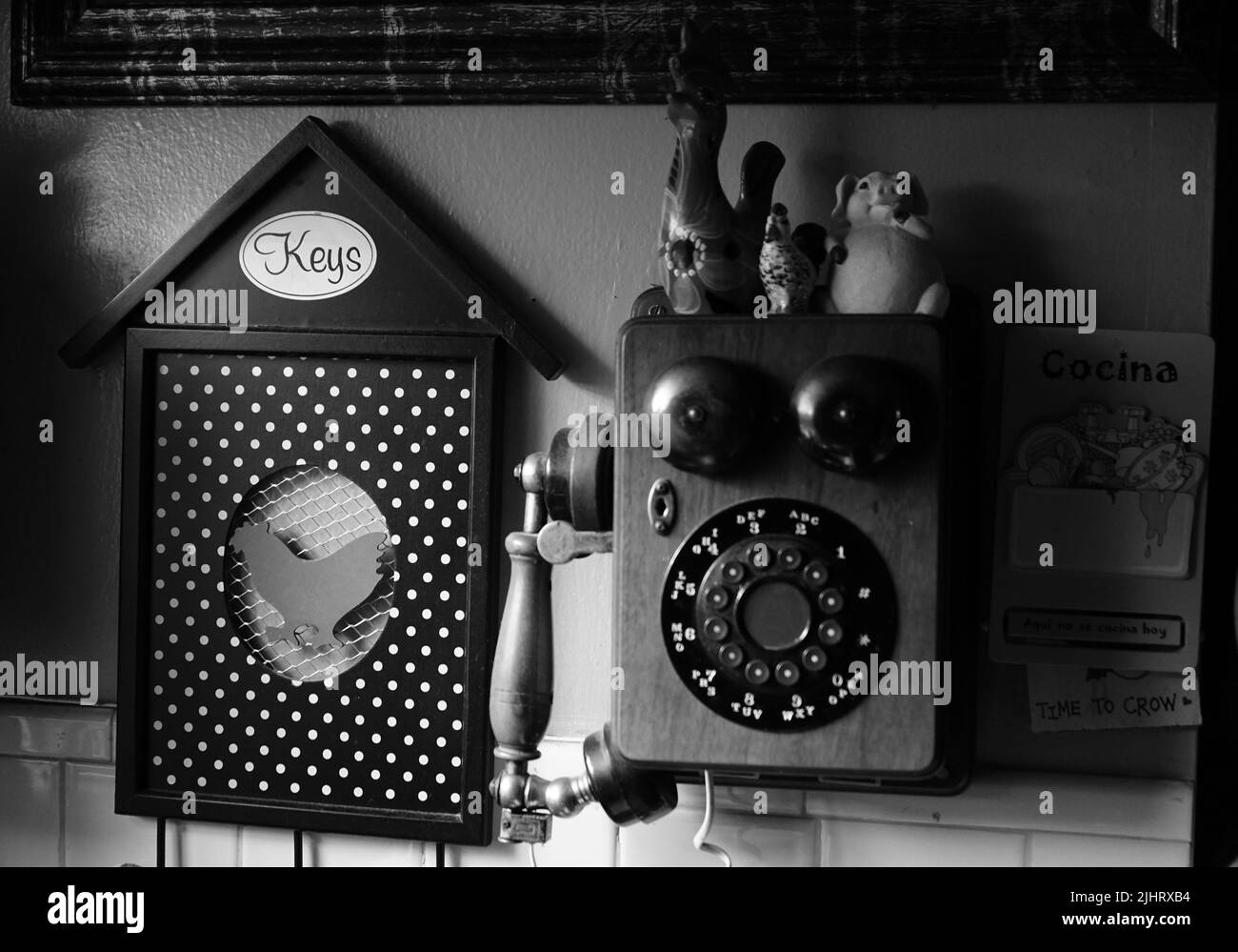 A grayscale of an old vintage telephone with wooden figurines on top ...