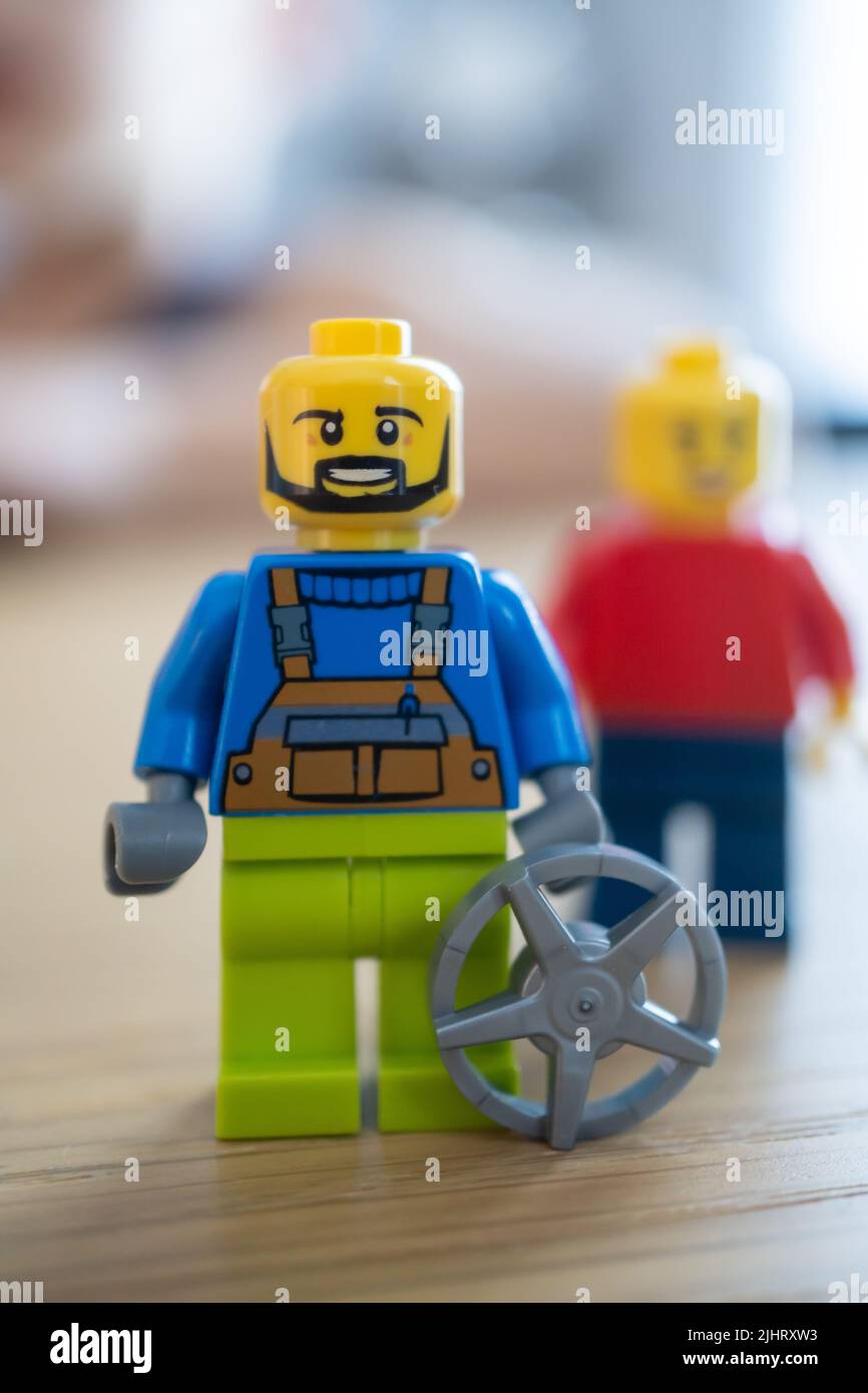 A vertical shot of a bearded Lego male figurine holding a wheel Stock ...