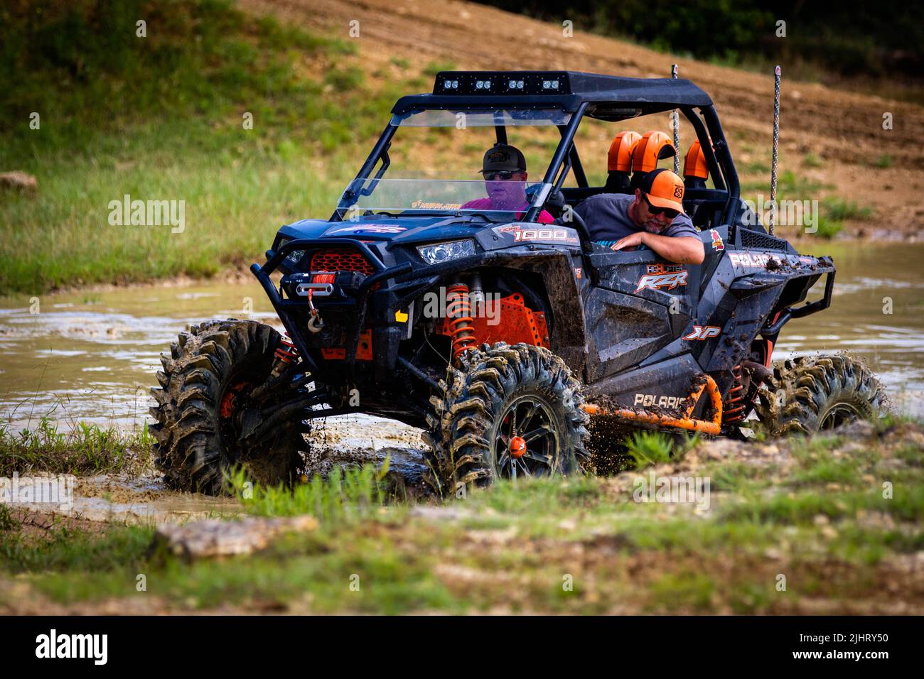 An ATV with people driving around and racing on a dirty muddy field at ...