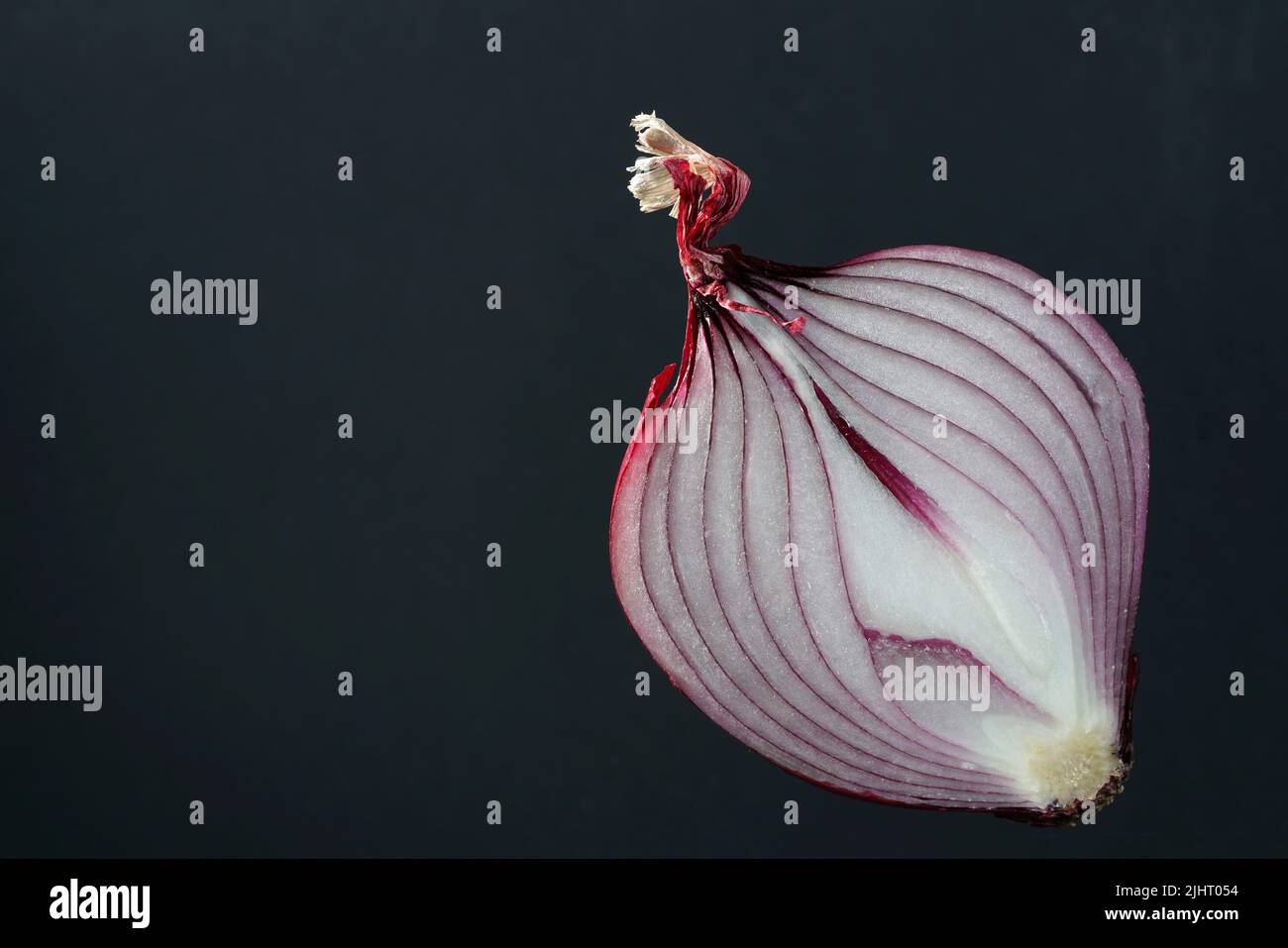 A red onion cut in a half isolated on black background Stock Photo - Alamy