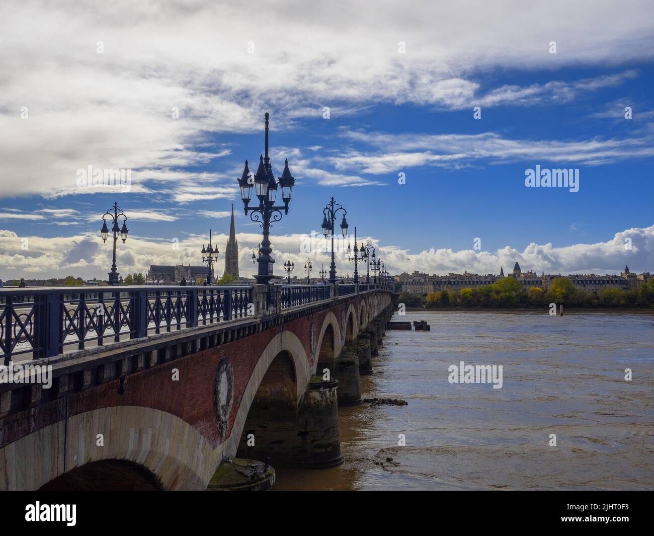 Stone bridge on the Garonne river in Bordeaux with St Michel cathedral ...