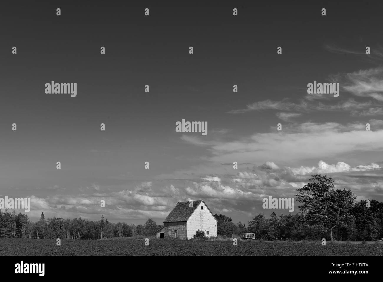 A grayscale of a lone house in the middle of a field Stock Photo - Alamy