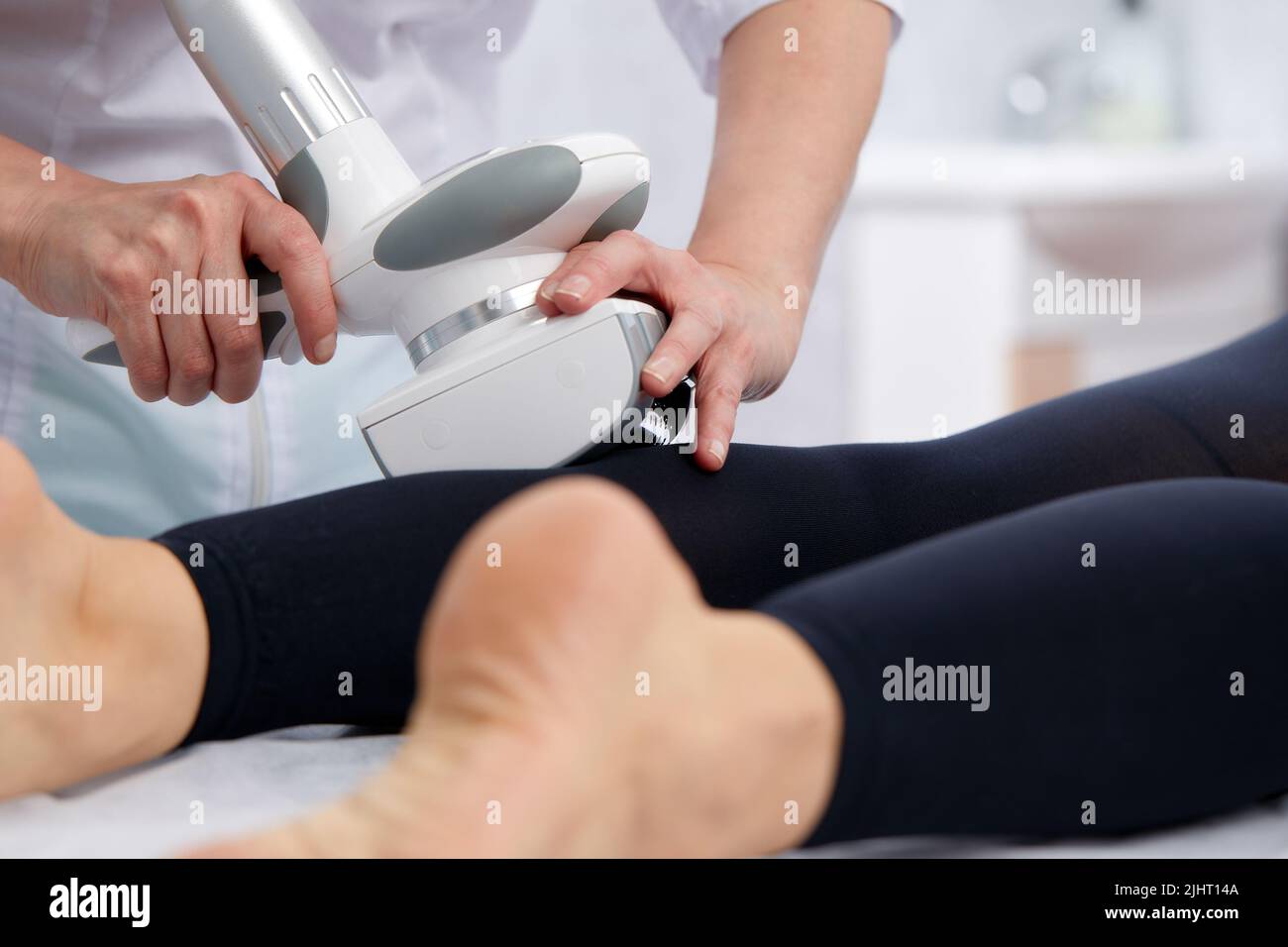 Beautician makes LPG calf massage of legs to young woman in black suit ...