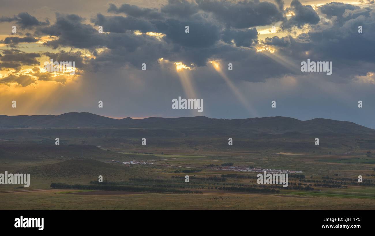The sun shines through the clouds above the landscape Stock Photo - Alamy