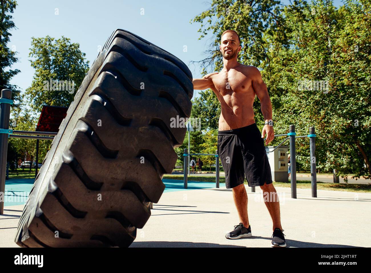Strong man training workout lifting large tire outdoor gym. Sportive ...