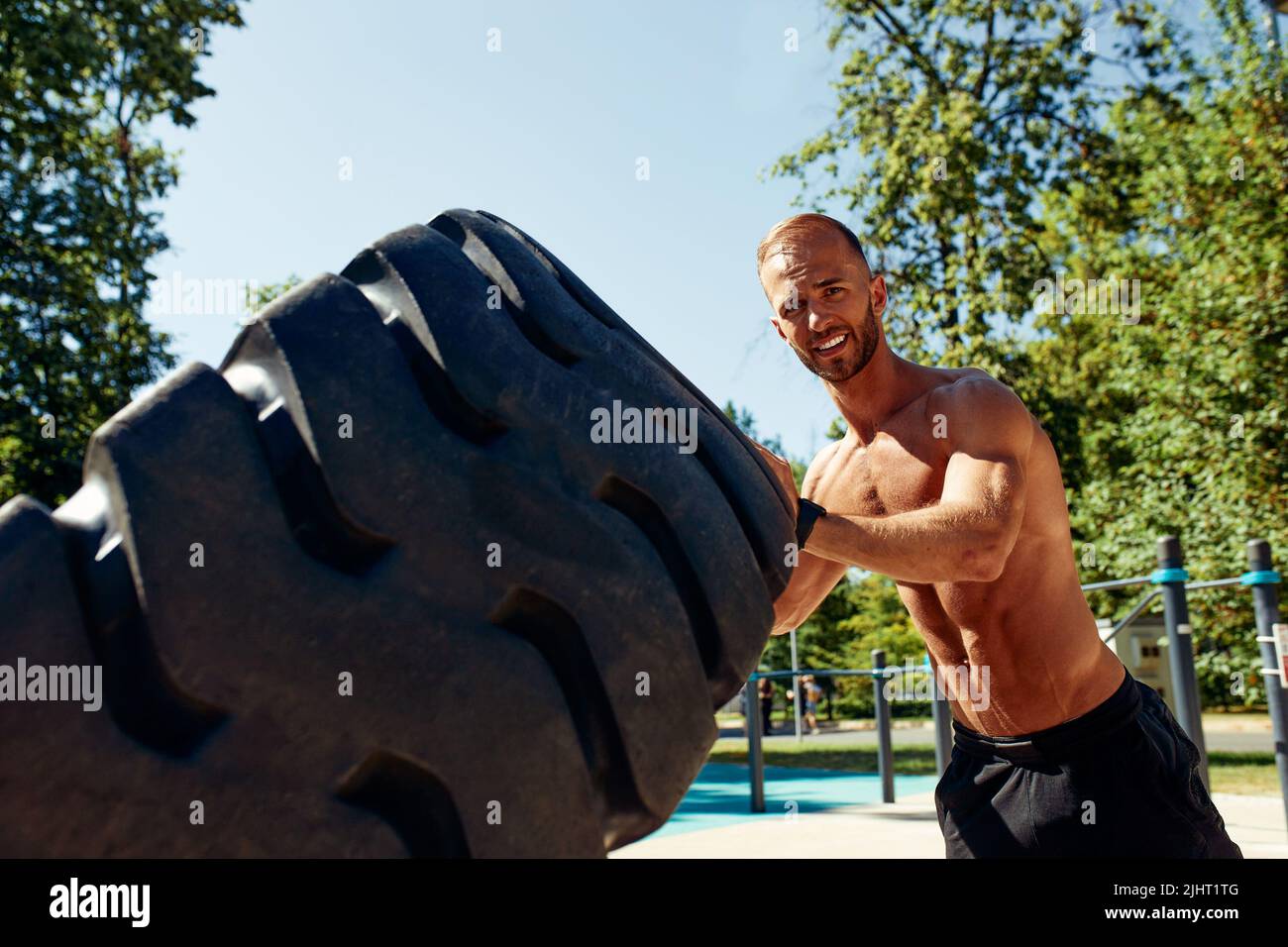 Strong man training workout lifting large tire outdoor gym. Sportive ...