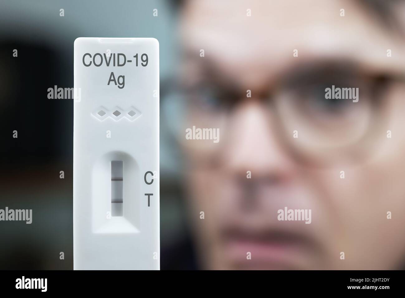 Covid-19 positive rapid test with blurred male face, with glases and ...