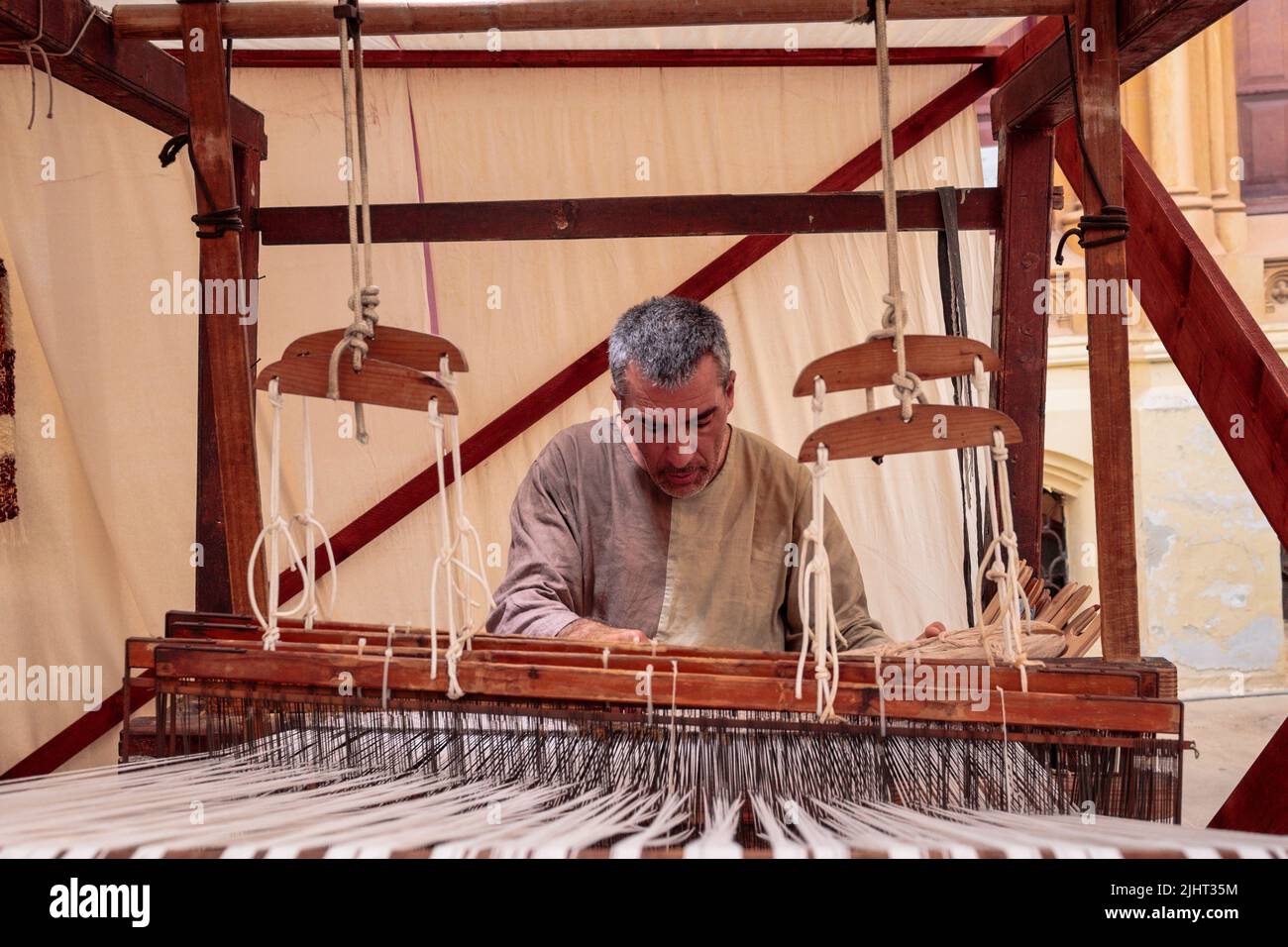 Medieval technology. Man demonstrating cloth weaving by a traditional ...