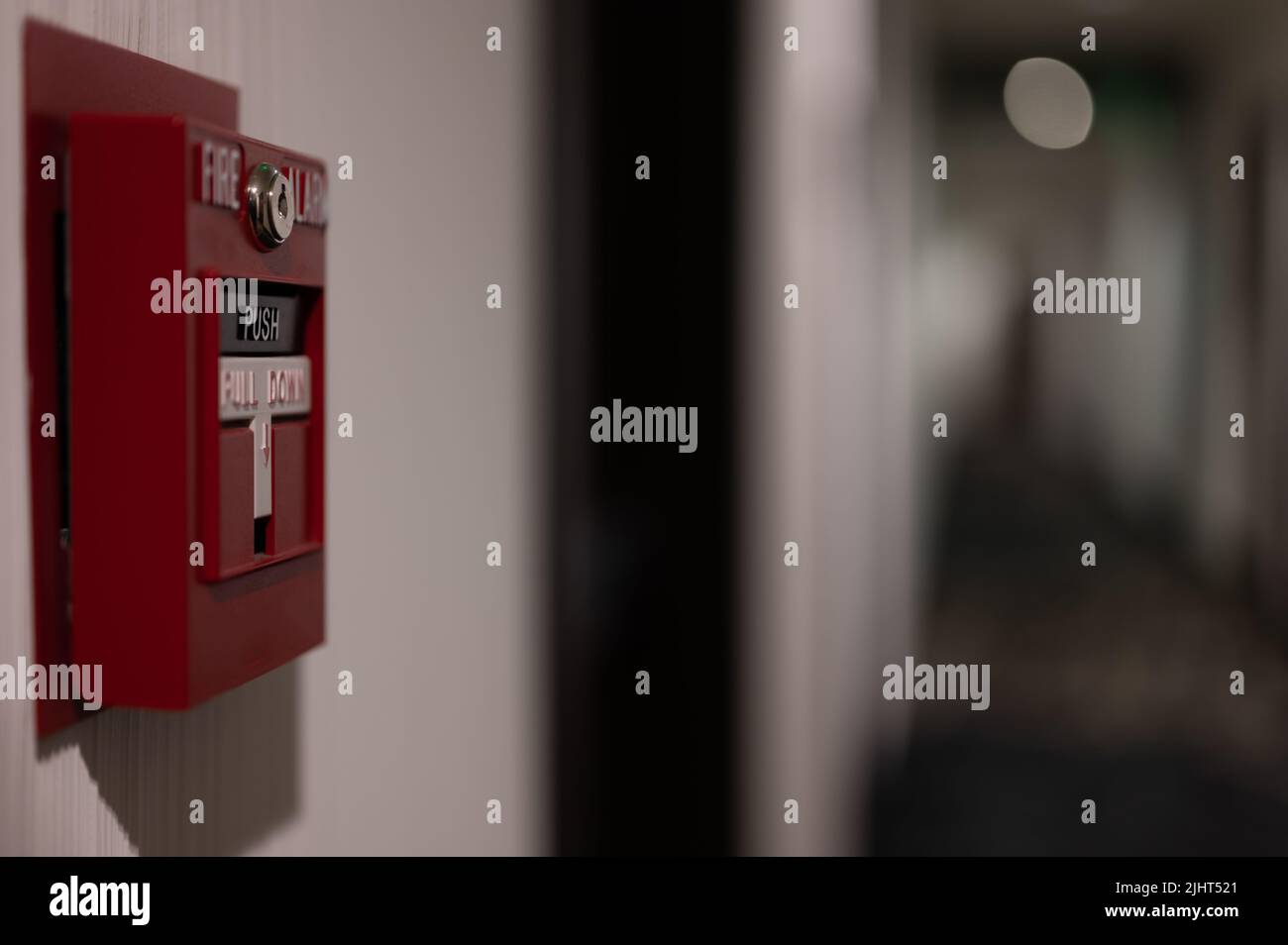 Selective focus on a wall mounted fire alarm switch in a empty hallway ...