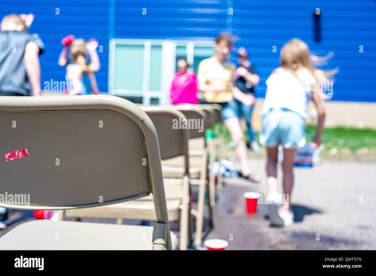 Selective focus on rows of metal folding chairs at an outdoor school ...