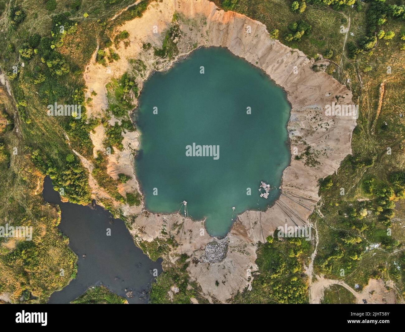 An aerial view of two lakes in the crater surrounded by greenery in ...
