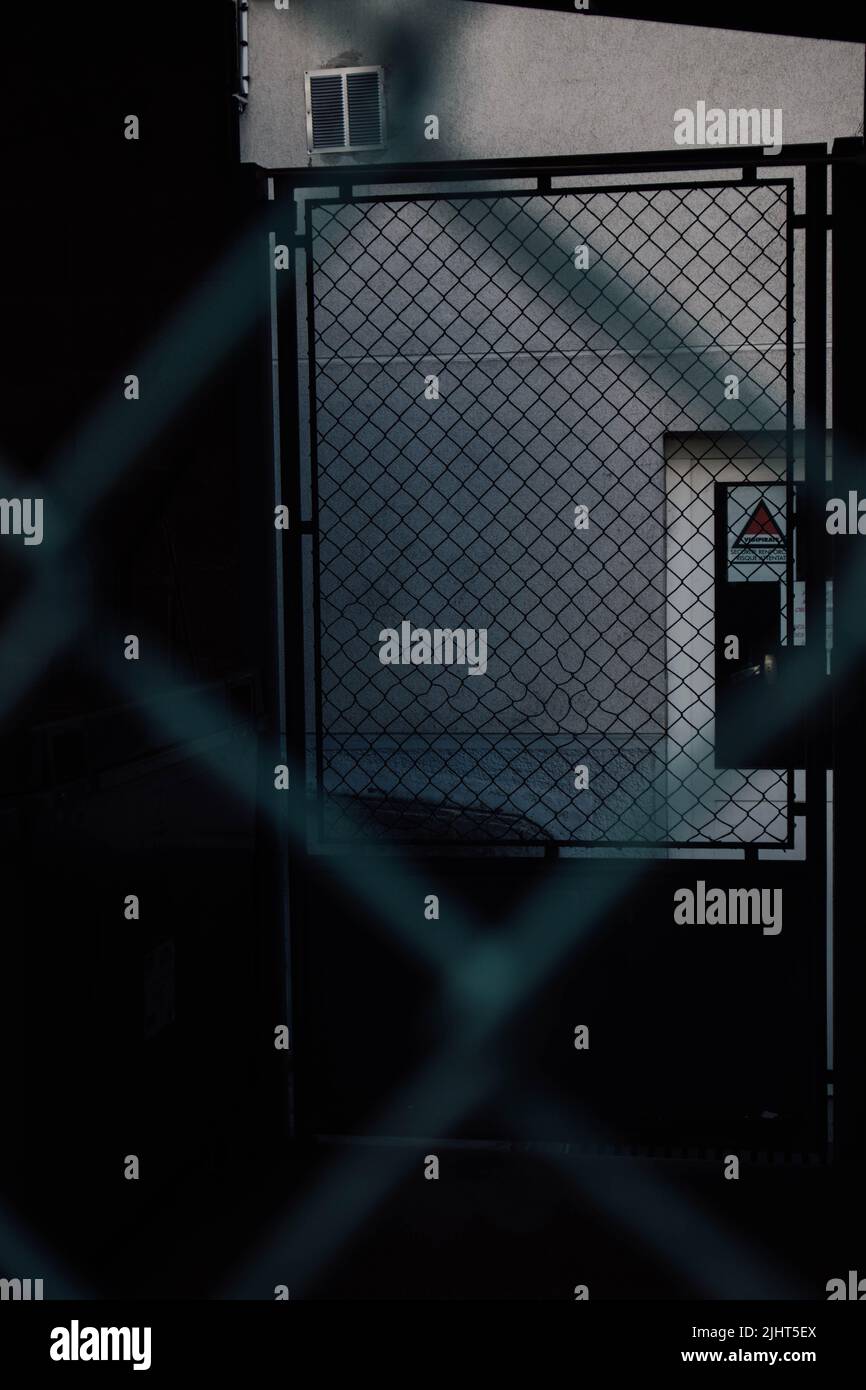 A vertical shot of dark area with mesh wire fence in front of a ...