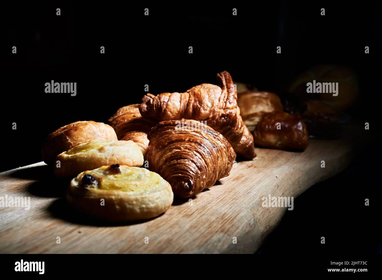 A wooden board with various types of pastries and toppings on a black ...