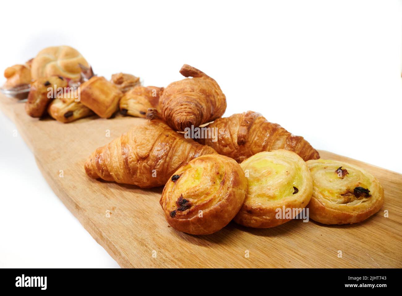 A wooden board with various types of pastries and toppings on a white ...