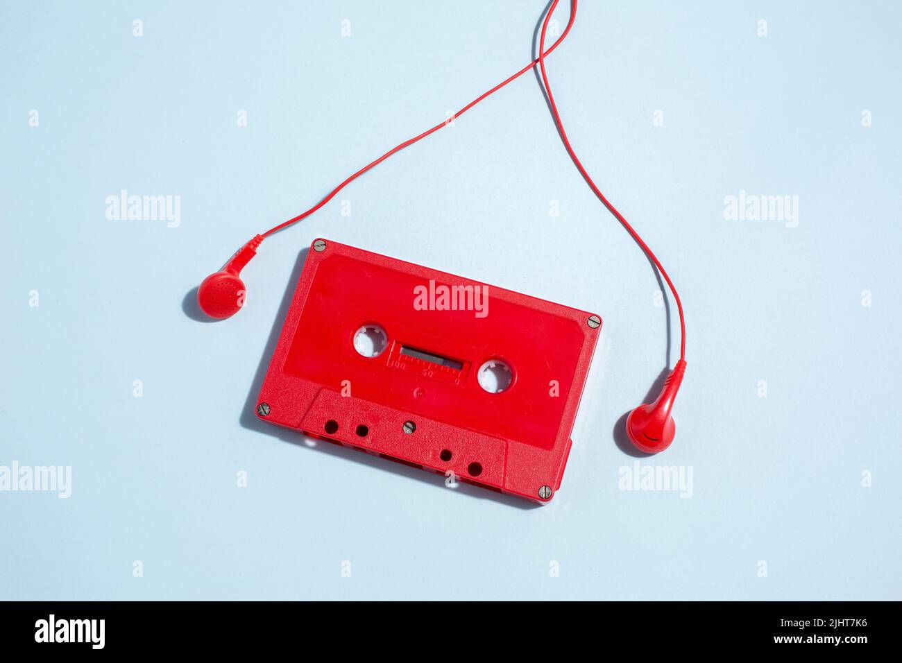 A red cassette with earphones on light blue background Stock Photo - Alamy