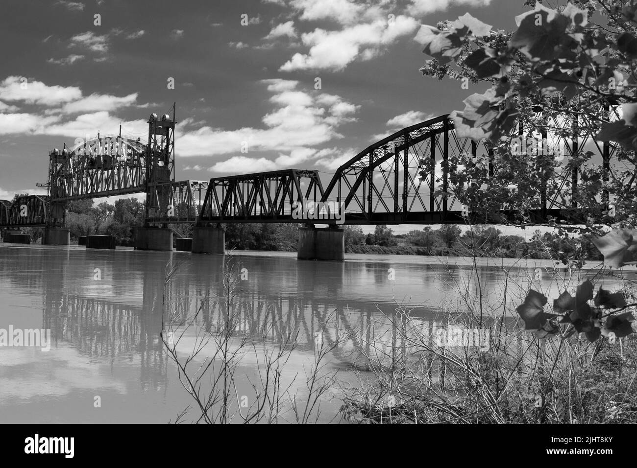 A grayscale of a Metal Bridge above a calm river in a daylight Stock ...