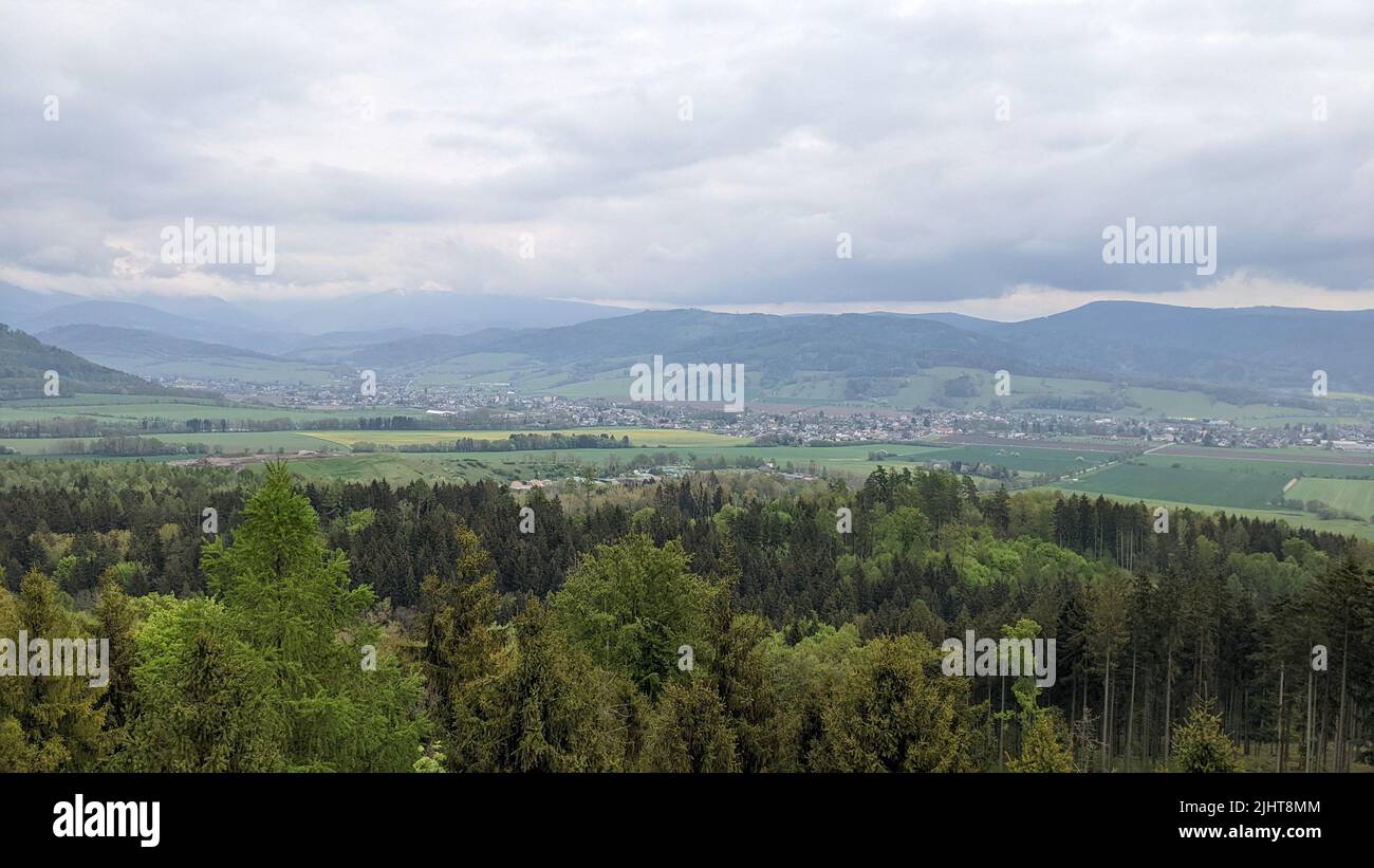 A beautiful view of a forest with hills and buildings in the background ...