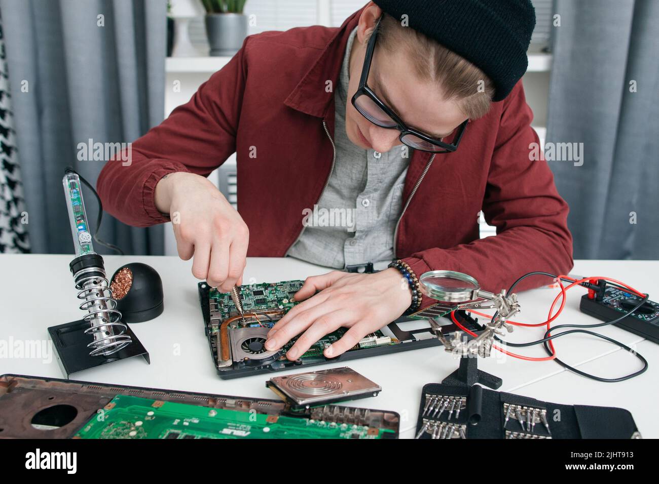 Young man disassembling computer motherboard Stock Photo - Alamy