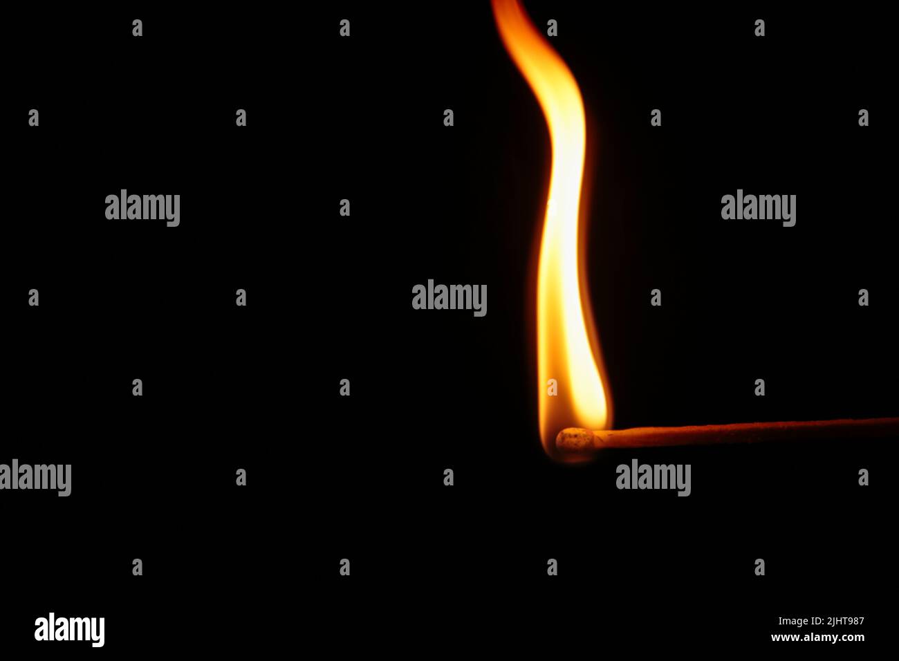 A closeup of a lighted match with strong flame on black background ...