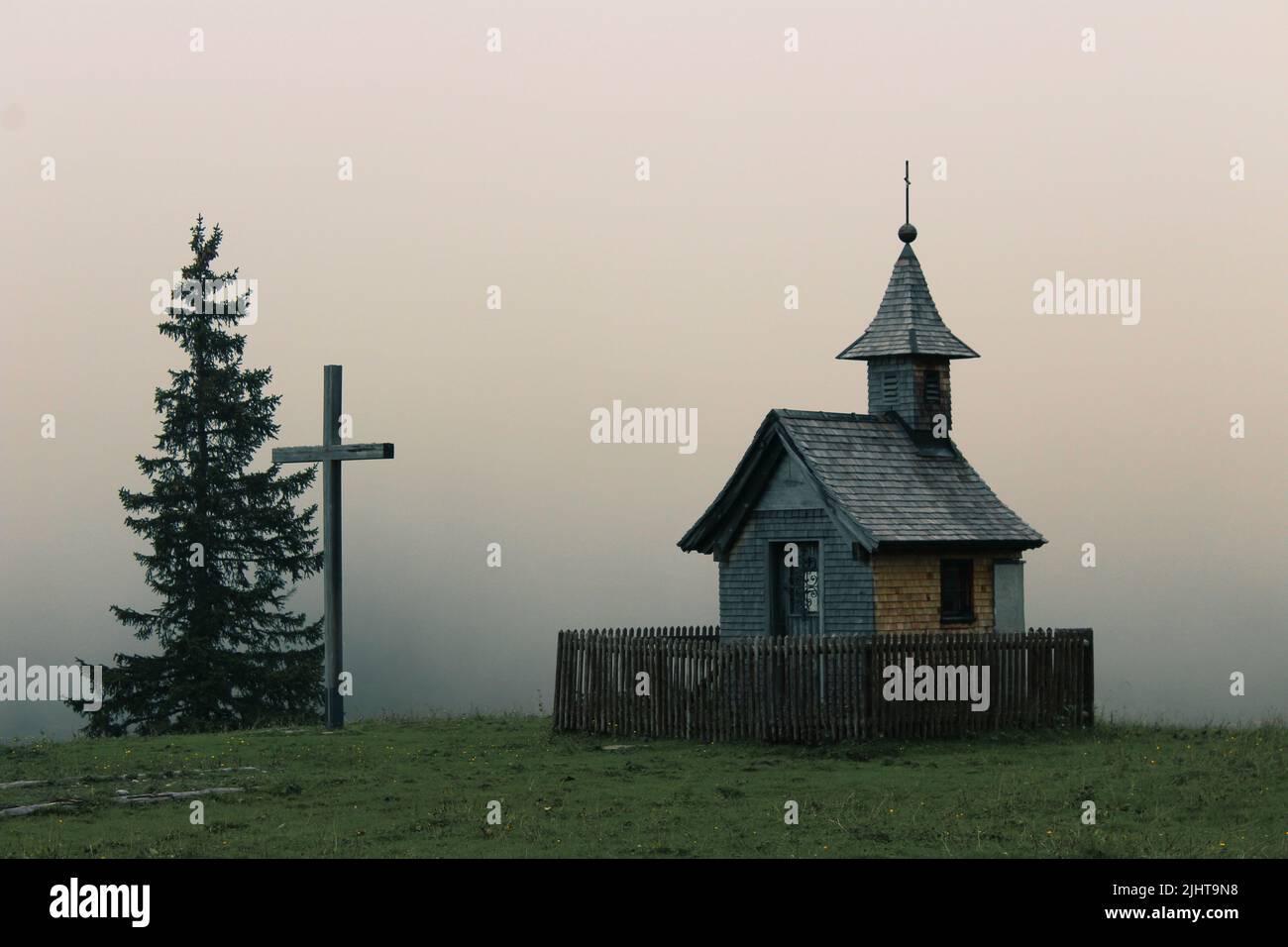 A scenic shot of a small wooden chapel with a large cross on the side ...