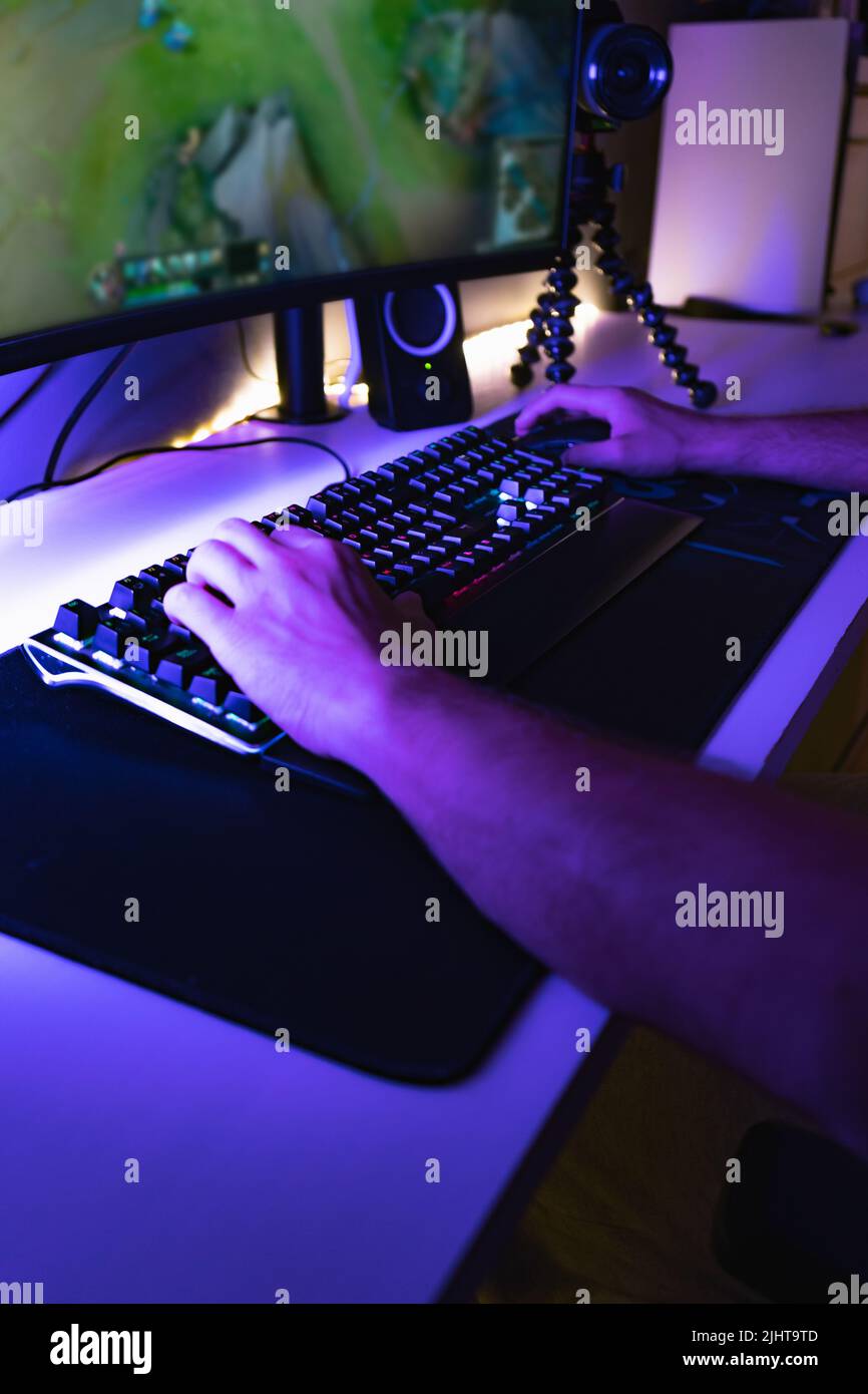 A vertical shot of hands on a mouse and keyboard playing a game on a PC ...