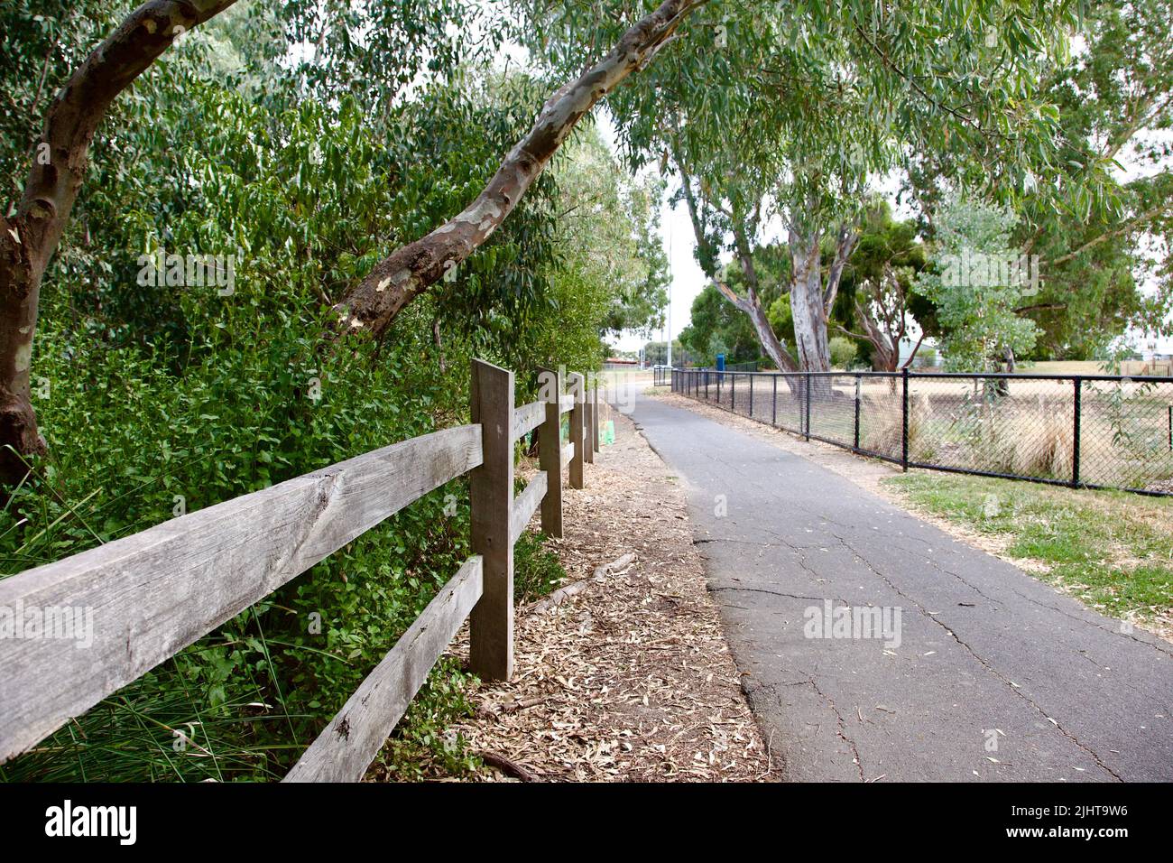 A city park pedestrian asphalt path wooden and metal fences on the ...