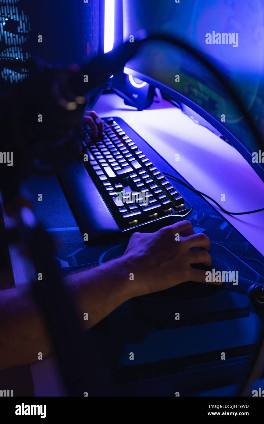 A vertical shot of hands on a mouse and keyboard playing a game on a PC ...