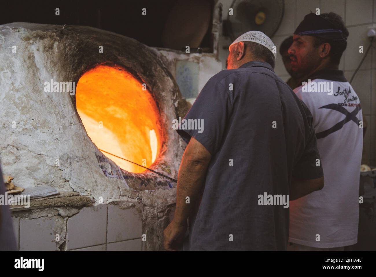 The men working in a bakery cooking bread in traditional oven in city ...
