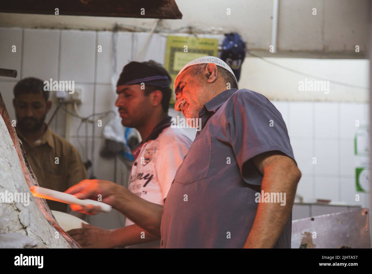 The men working in a bakery cooking bread in traditional oven in city ...
