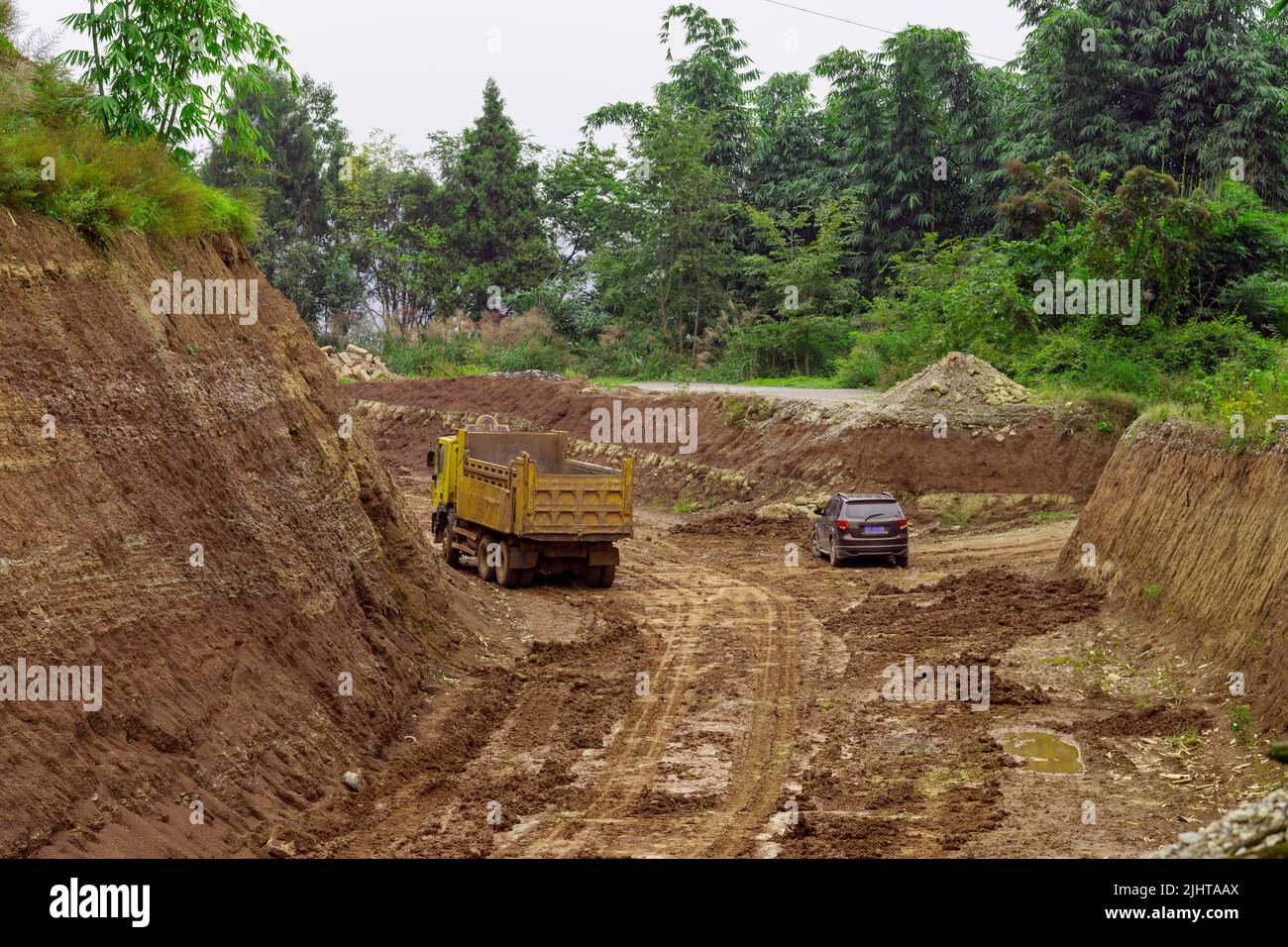 An old truck driving on a muddy road surrounded by rocks in a rural ...
