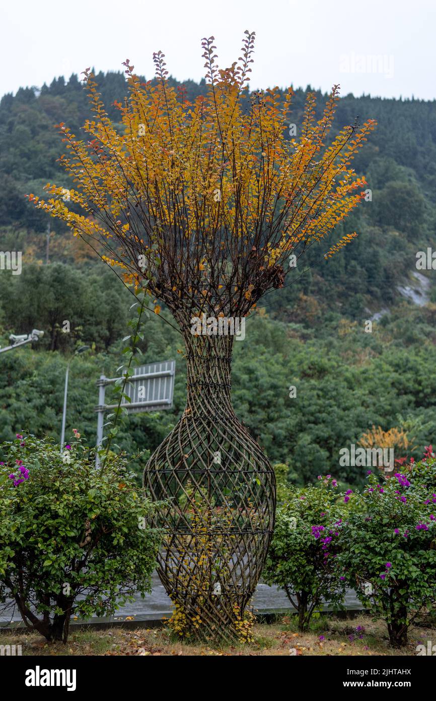 A vertical shot of a tree with beautiful yellow flowers in a huge vase ...