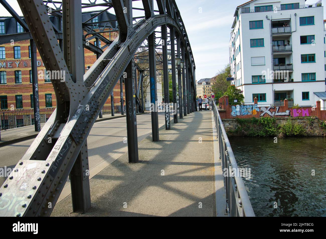 A bridge with metal railings over the river and graffiti in the ...