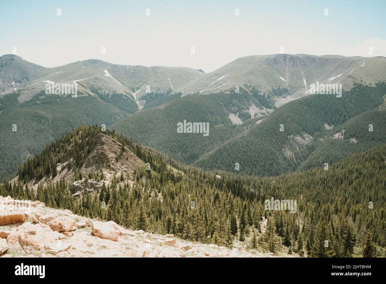 A mesmerizing view from hill to forested mountain range on sunny day in ...