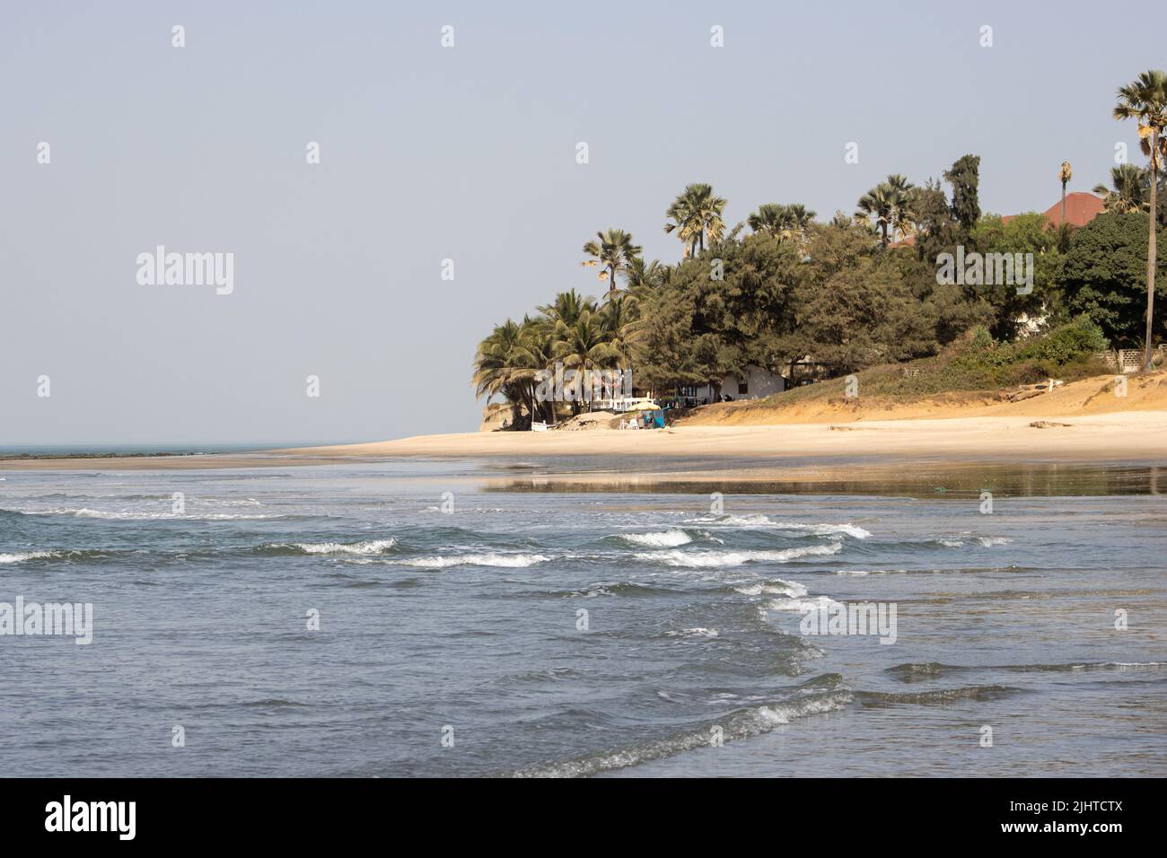 wide tropical beach palm trees and small waves and yellow sand headland ...
