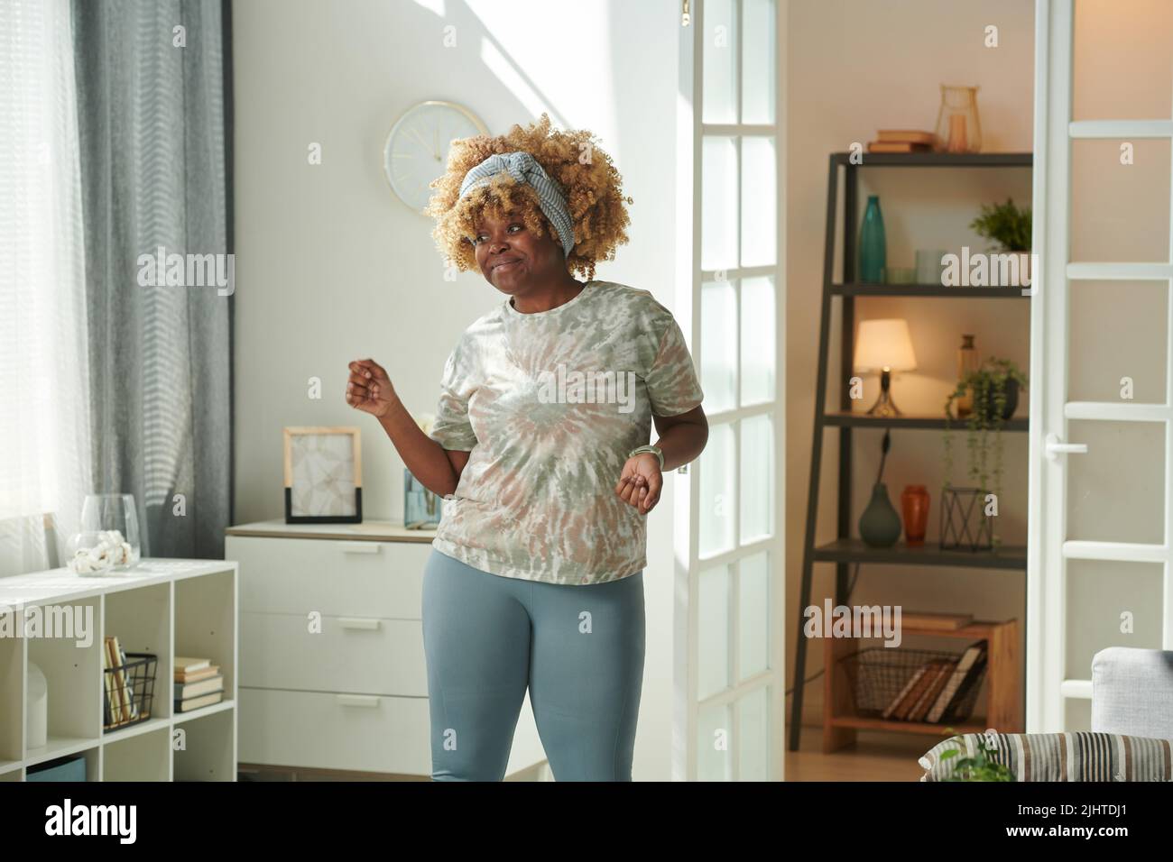 African young woman dancing to music during her morning exercises at ...